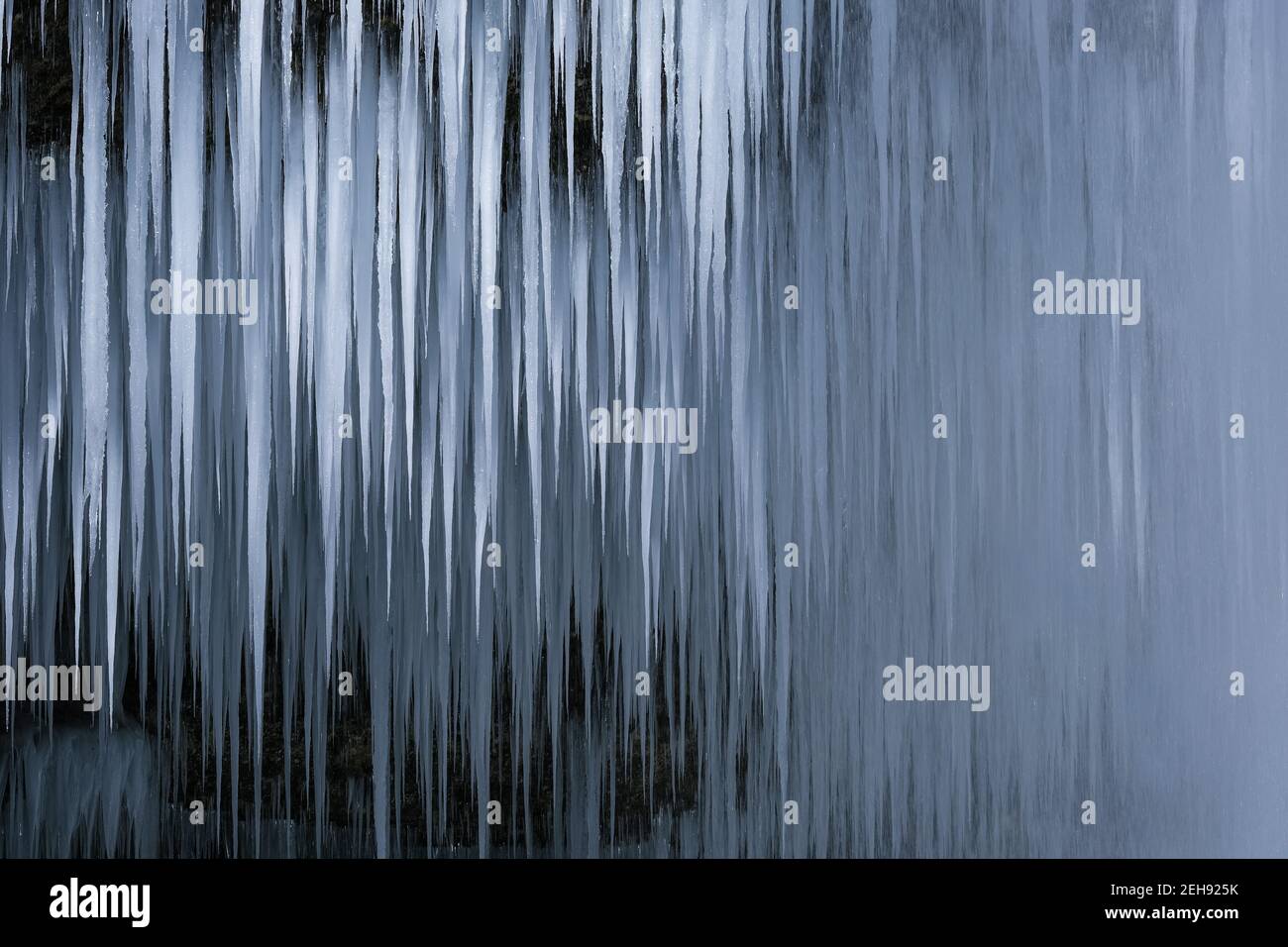 Beautiful long icicles of a frozen waterfall. Water flowing and ...