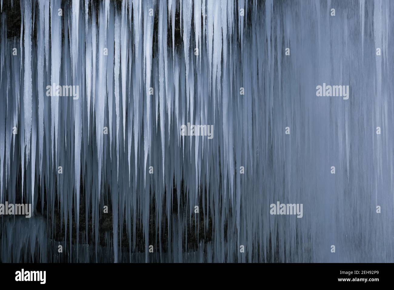 Beautiful long icicles of a frozen waterfall. Water flowing and ...