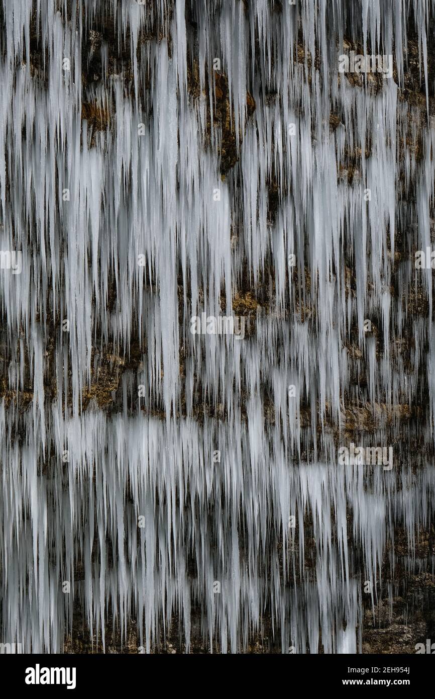 Beautiful long icicles of a frozen waterfall. Water flowing and ...