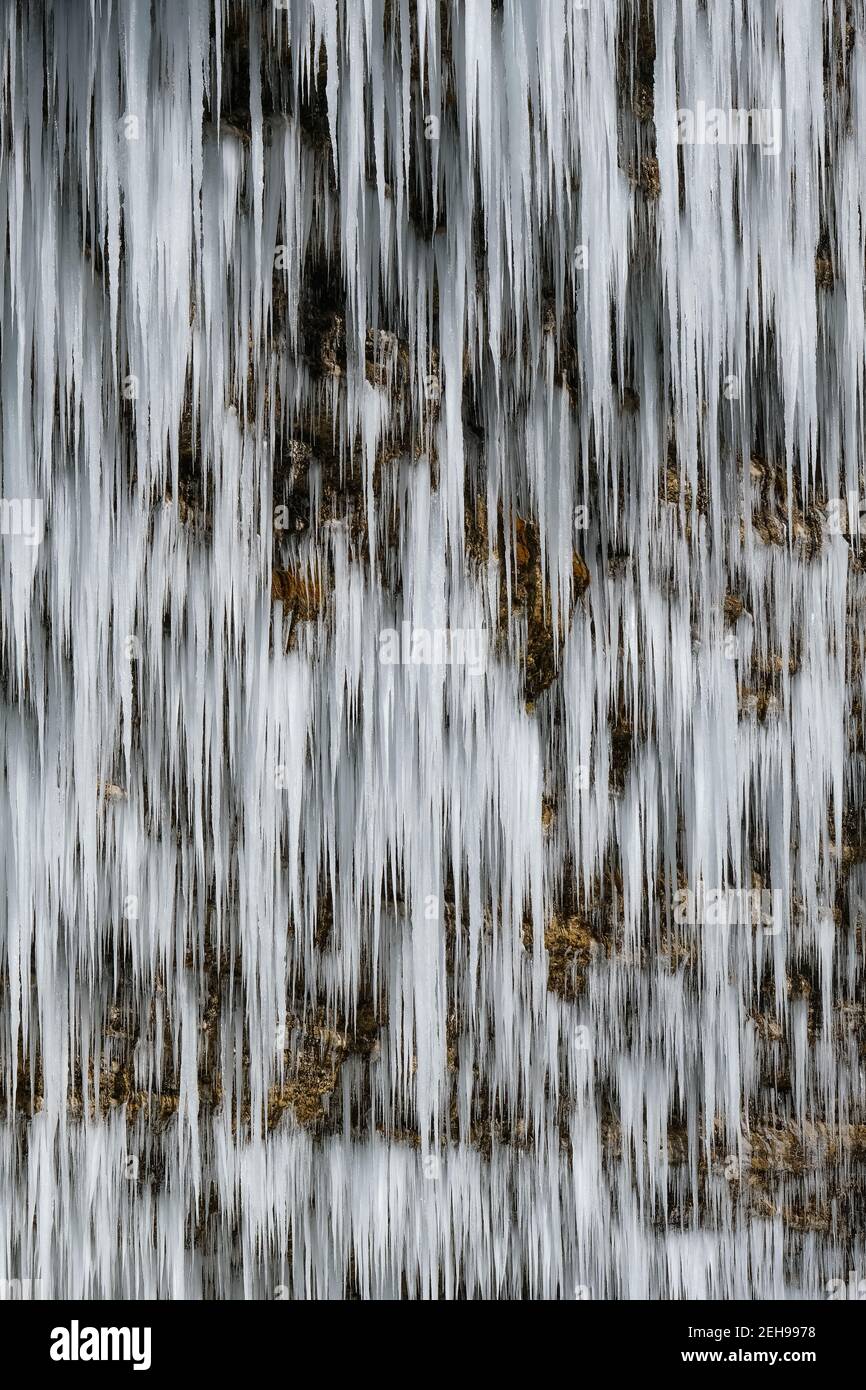 Beautiful long icicles of a frozen waterfall. Water flowing and ...