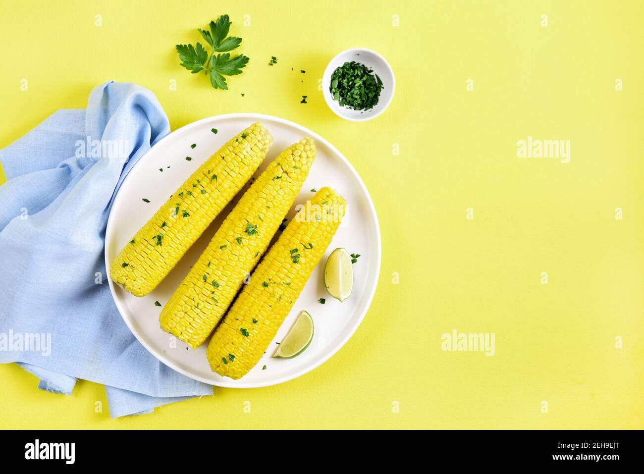 Boiled corn cobs on plate over yellow background with free text space ...