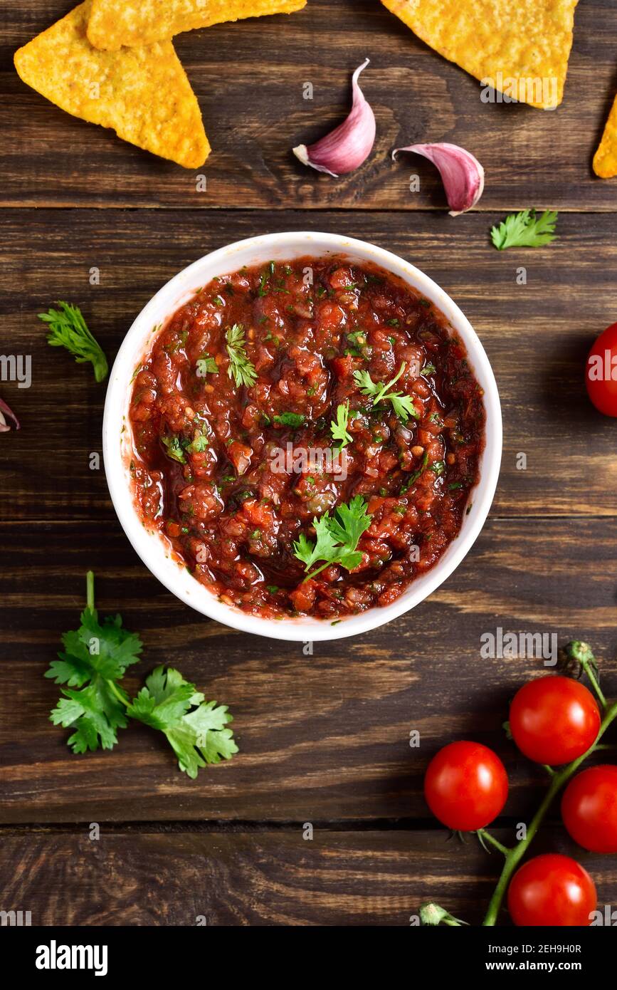 Homemade tomato salsa in bowl over wooden background. Top view, flat ...