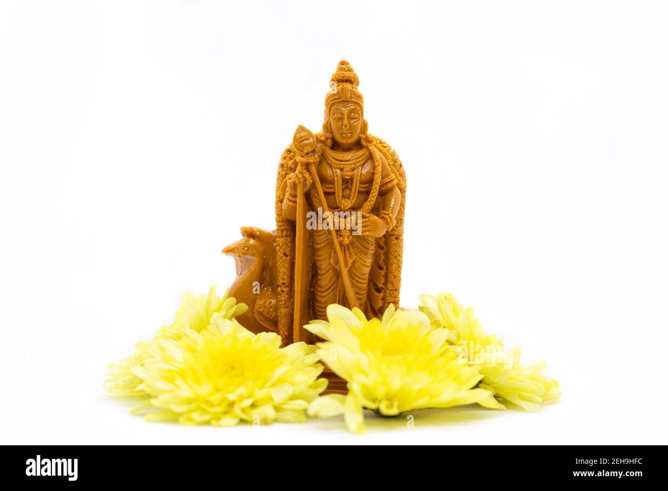 The wooden statue of Lord Murugan with yellow flowers is isolated on a ...