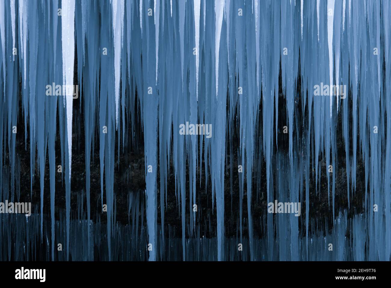 Beautiful long icicles of a frozen waterfall. Water flowing and ...