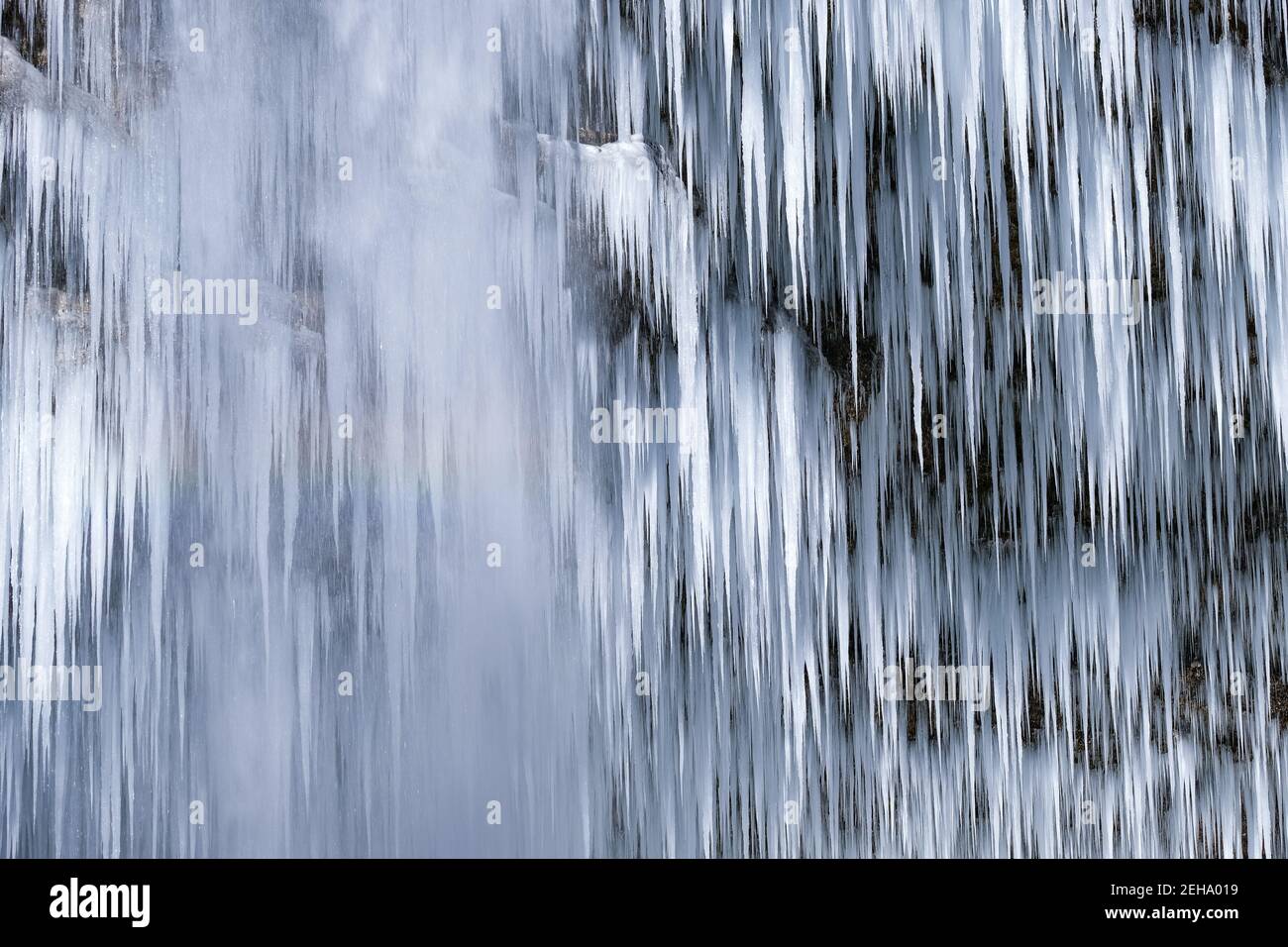 Beautiful long icicles of a frozen waterfall. Water flowing and ...