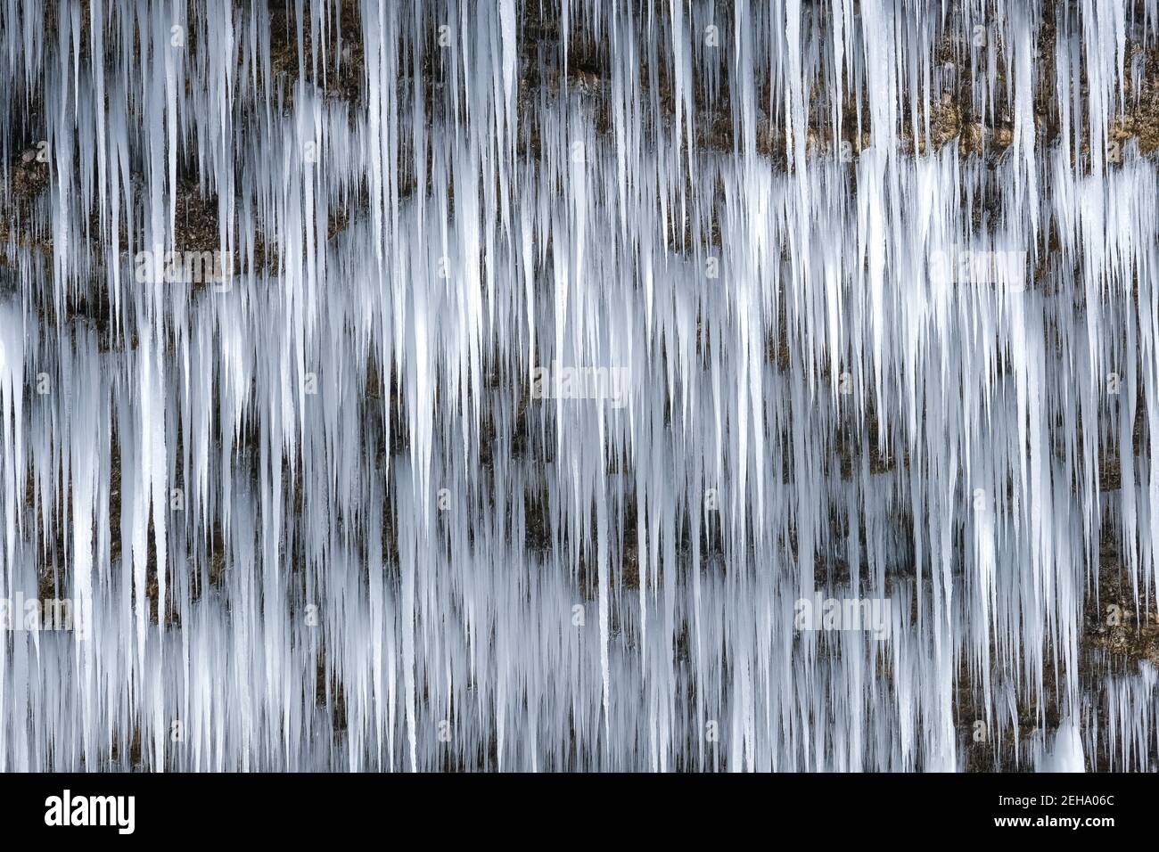 Beautiful long icicles of a frozen waterfall. Water flowing and ...
