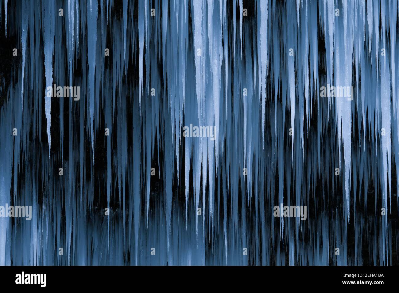 Beautiful long icicles of a frozen waterfall. Water flowing and ...