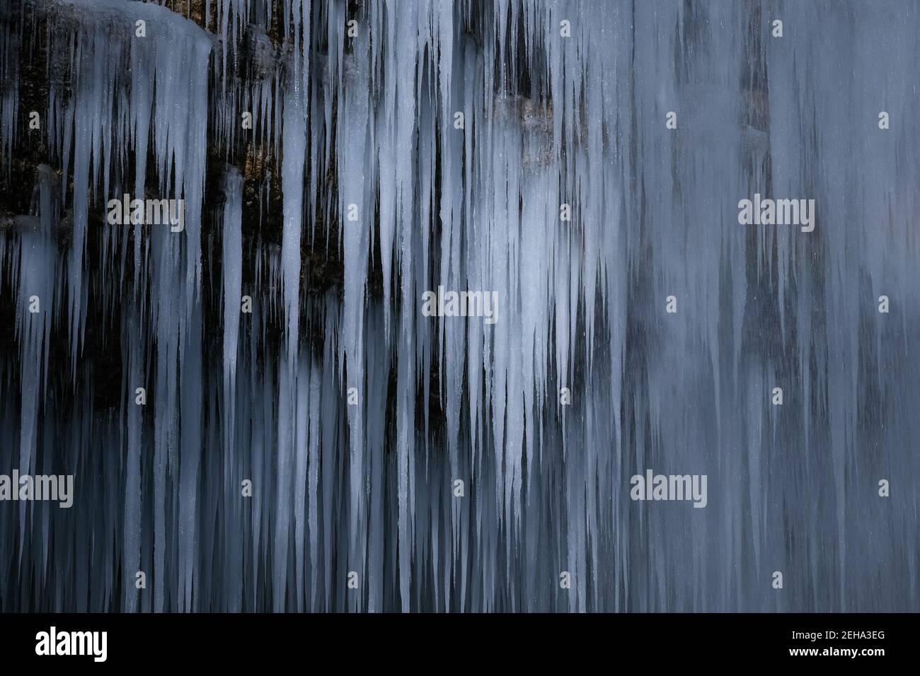 Beautiful long icicles of a frozen waterfall. Water flowing and ...
