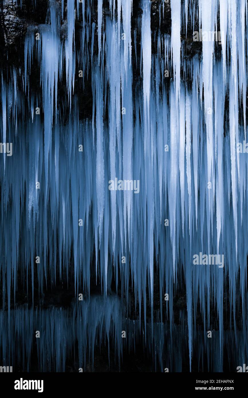 Beautiful long icicles of a frozen waterfall. Water flowing and ...