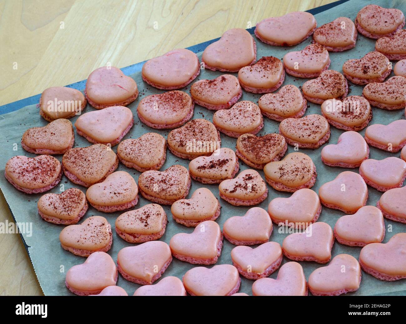 Pink heart homemade macaron cookies on parchment paper on a baking ...