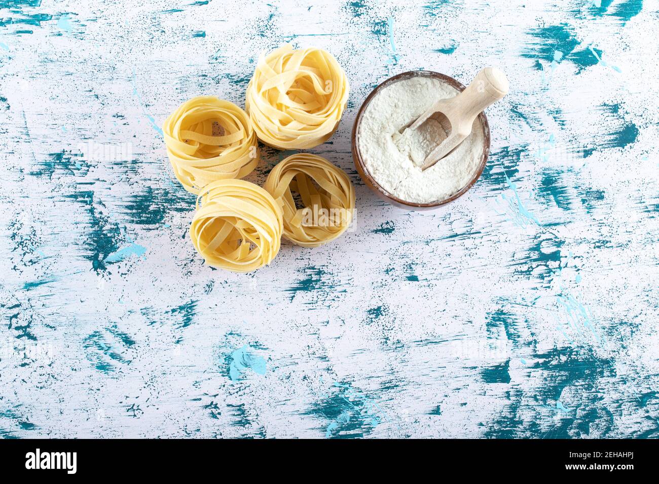 Dry tagliatelle nests and bowl of flour on colorful surface Stock Photo ...