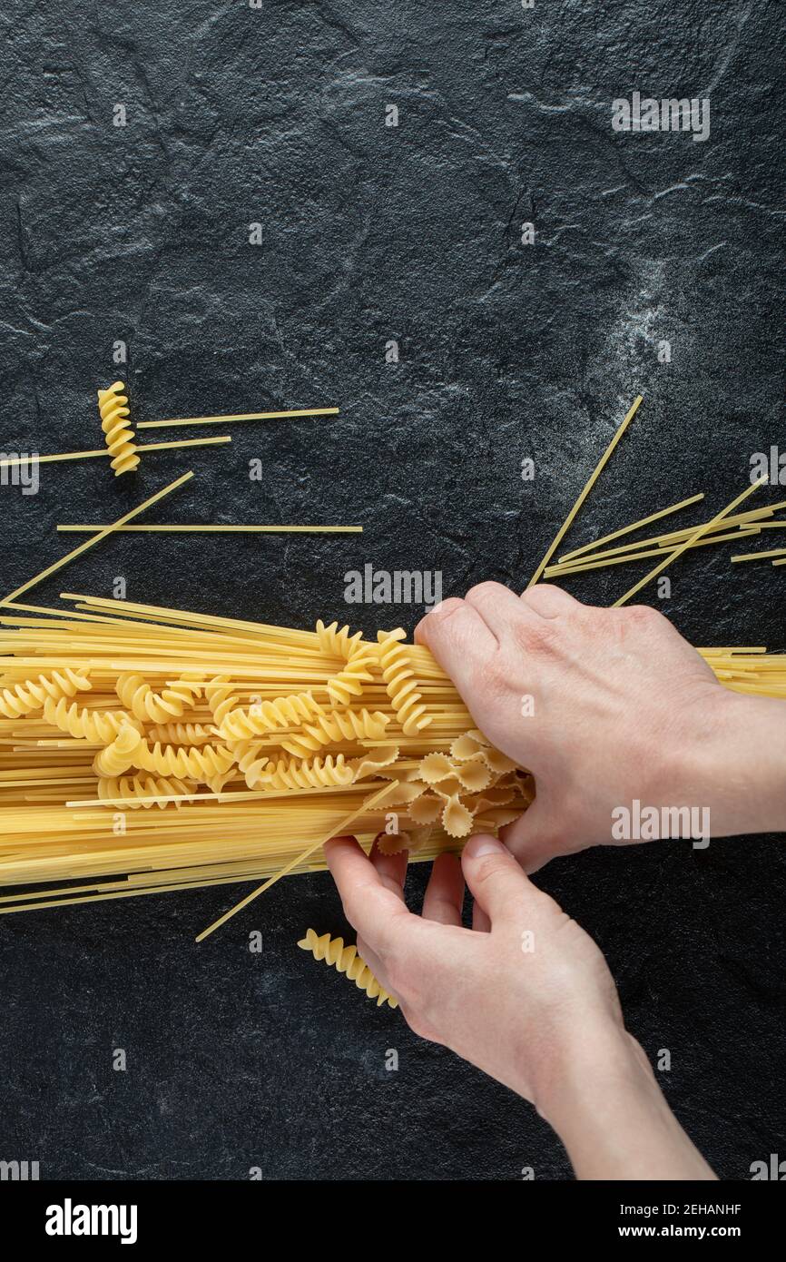 Woman hands holding spaghetti on dark background Stock Photo - Alamy