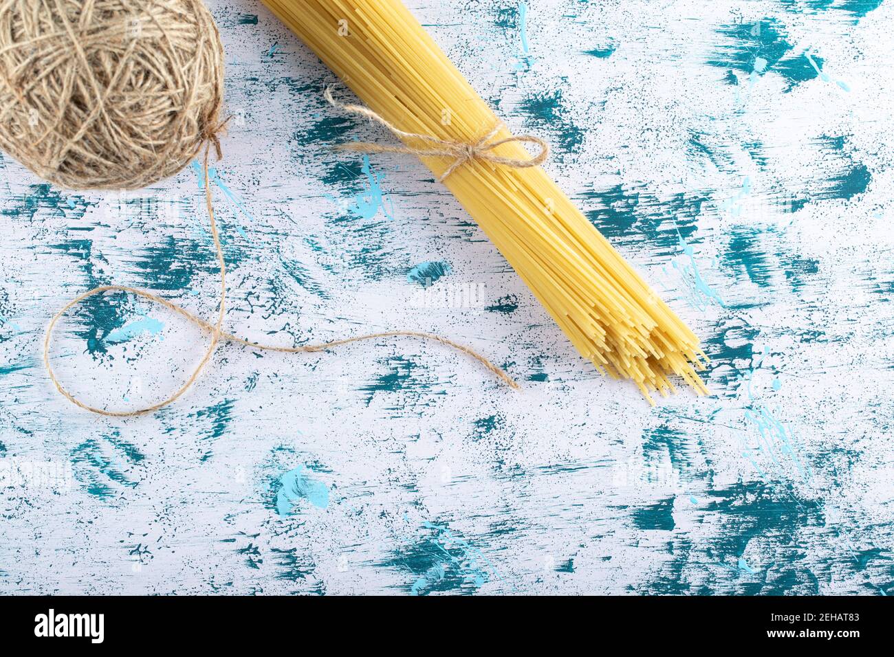 Uncooked spaghetti pasta and yarn on blue background Stock Photo - Alamy