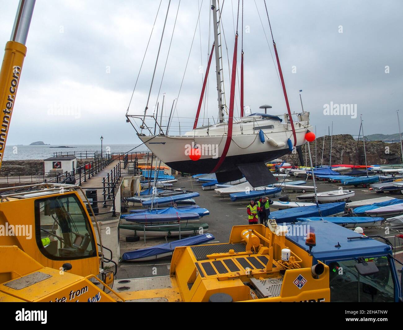 Sadler 25 yacht being craned into the harbour Stock Photo - Alamy