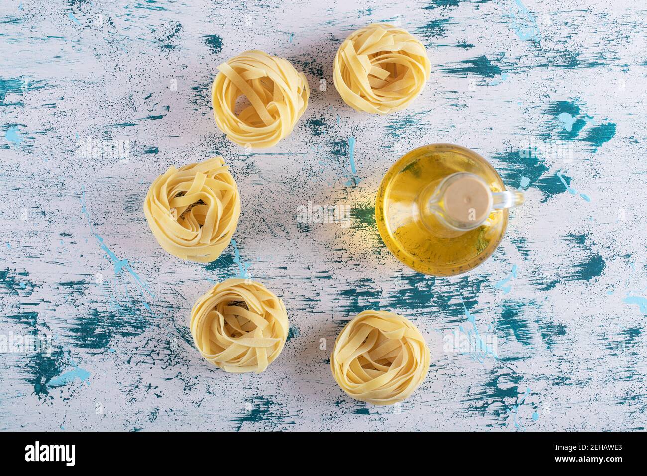 Tagliatelle nests and glass of olive oil on colorful background Stock ...