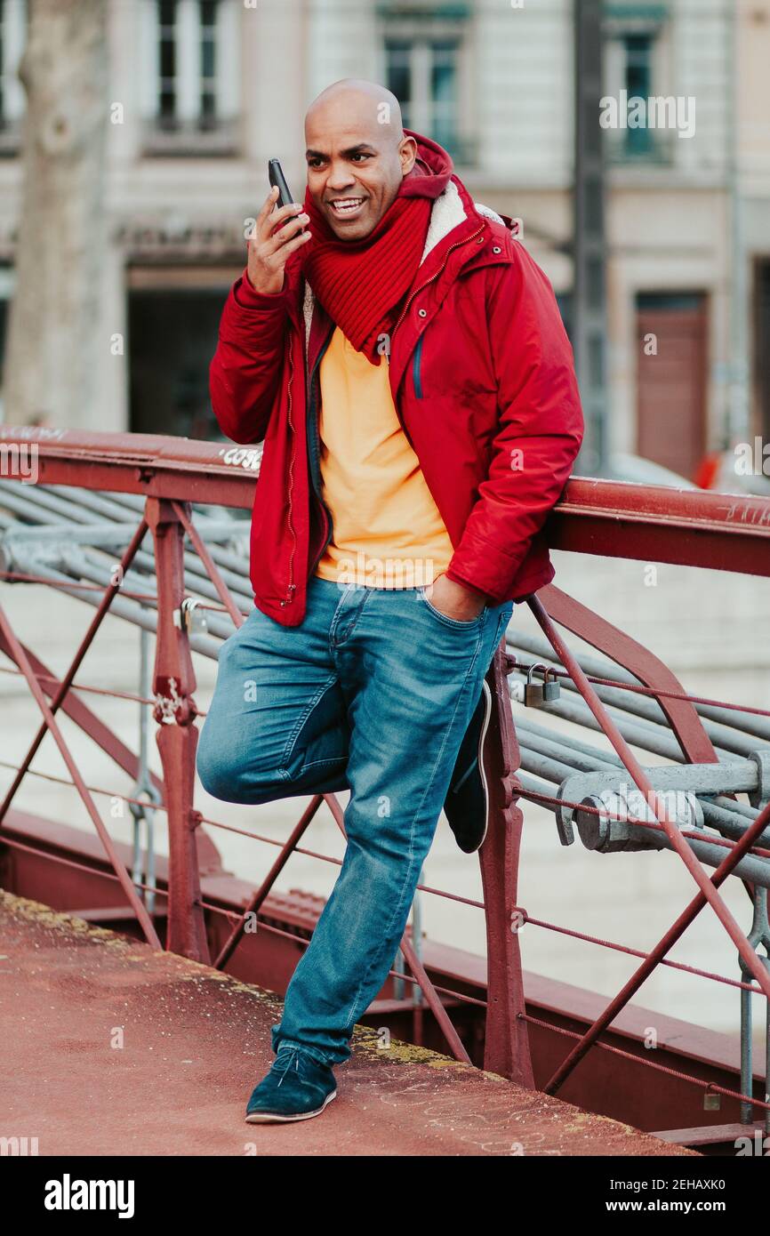 Young bald Latin male talking on his phone while walking in the city of ...