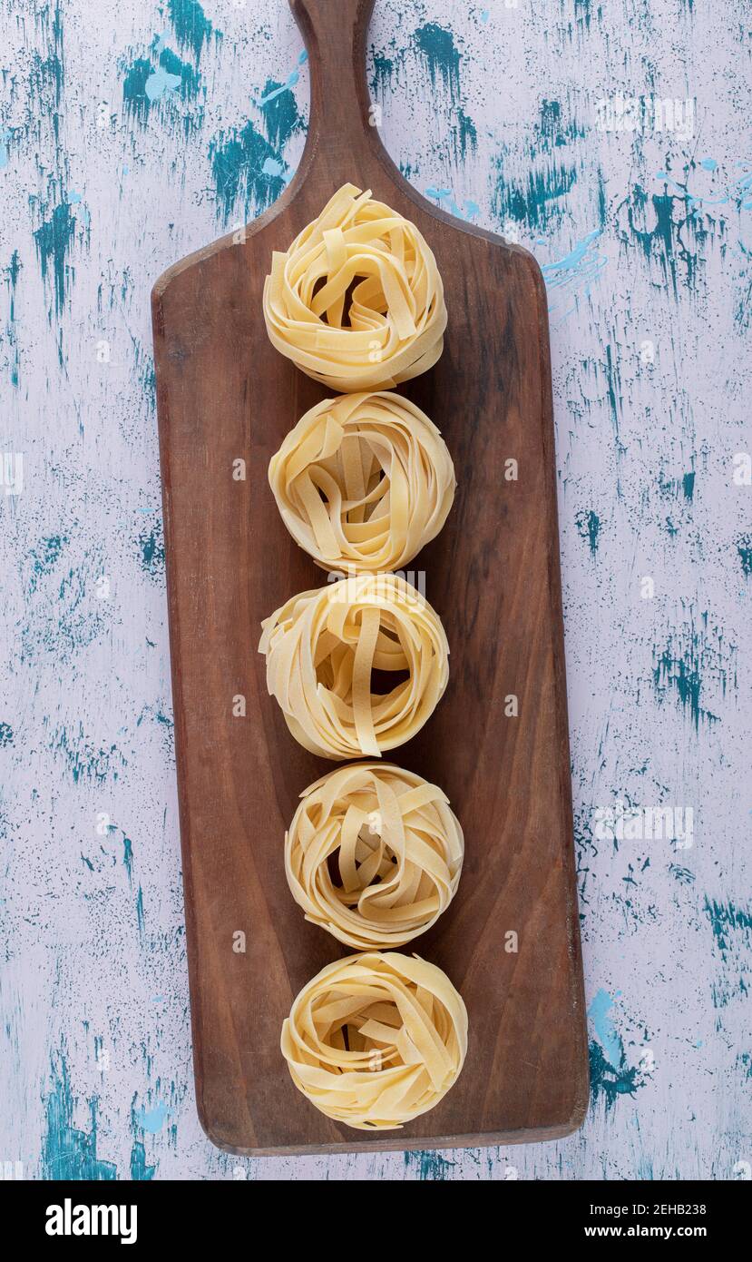 Raw tagliatelle nests on wooden board Stock Photo - Alamy