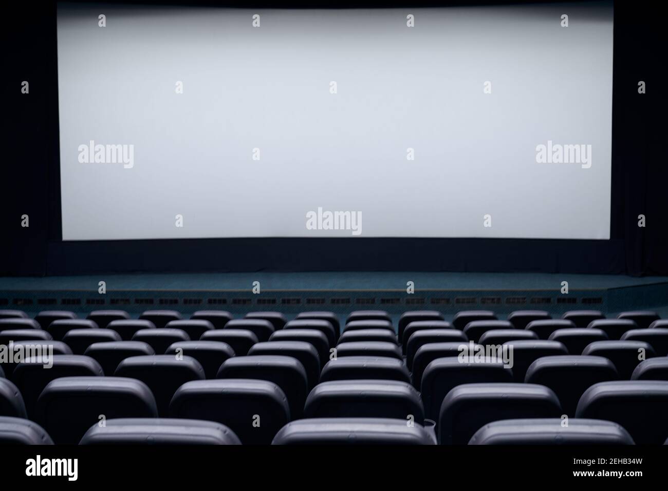Interior cinema hall with white screen and black comfortable chairs ...