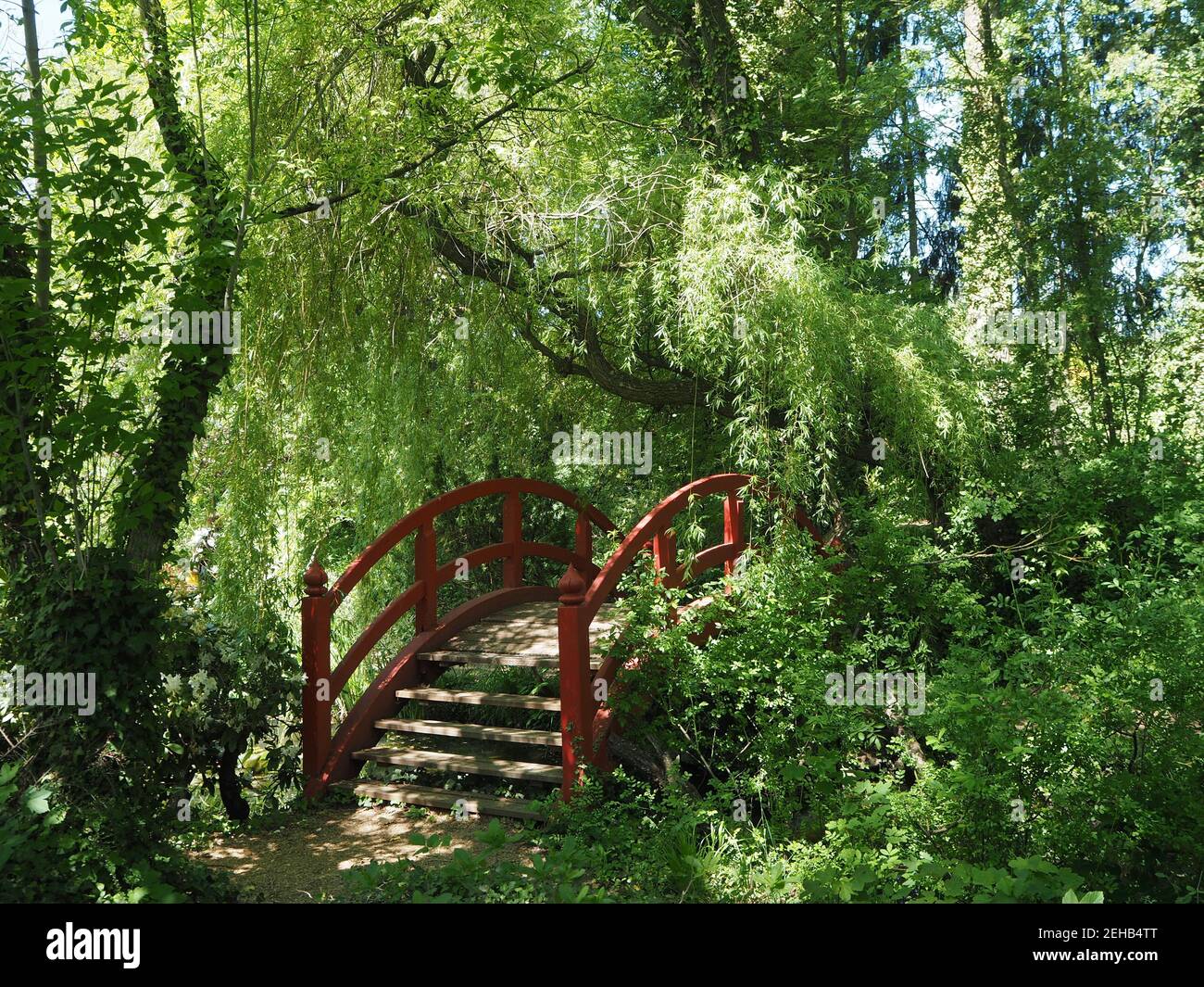 Red ornamental bridge in lush green park Stock Photo - Alamy