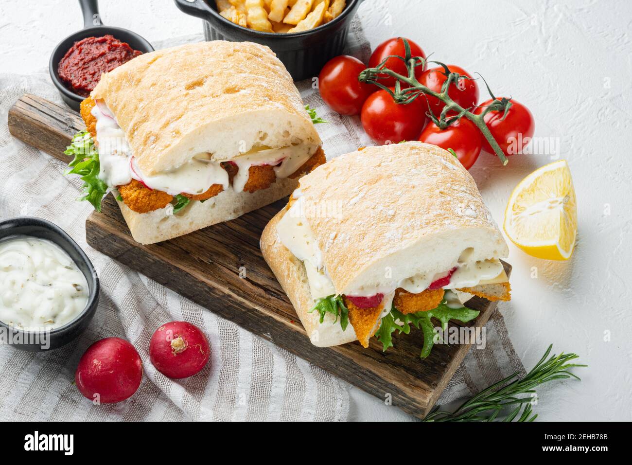 homemade baguette with crumbed fish set, on wooden cutting board, on ...