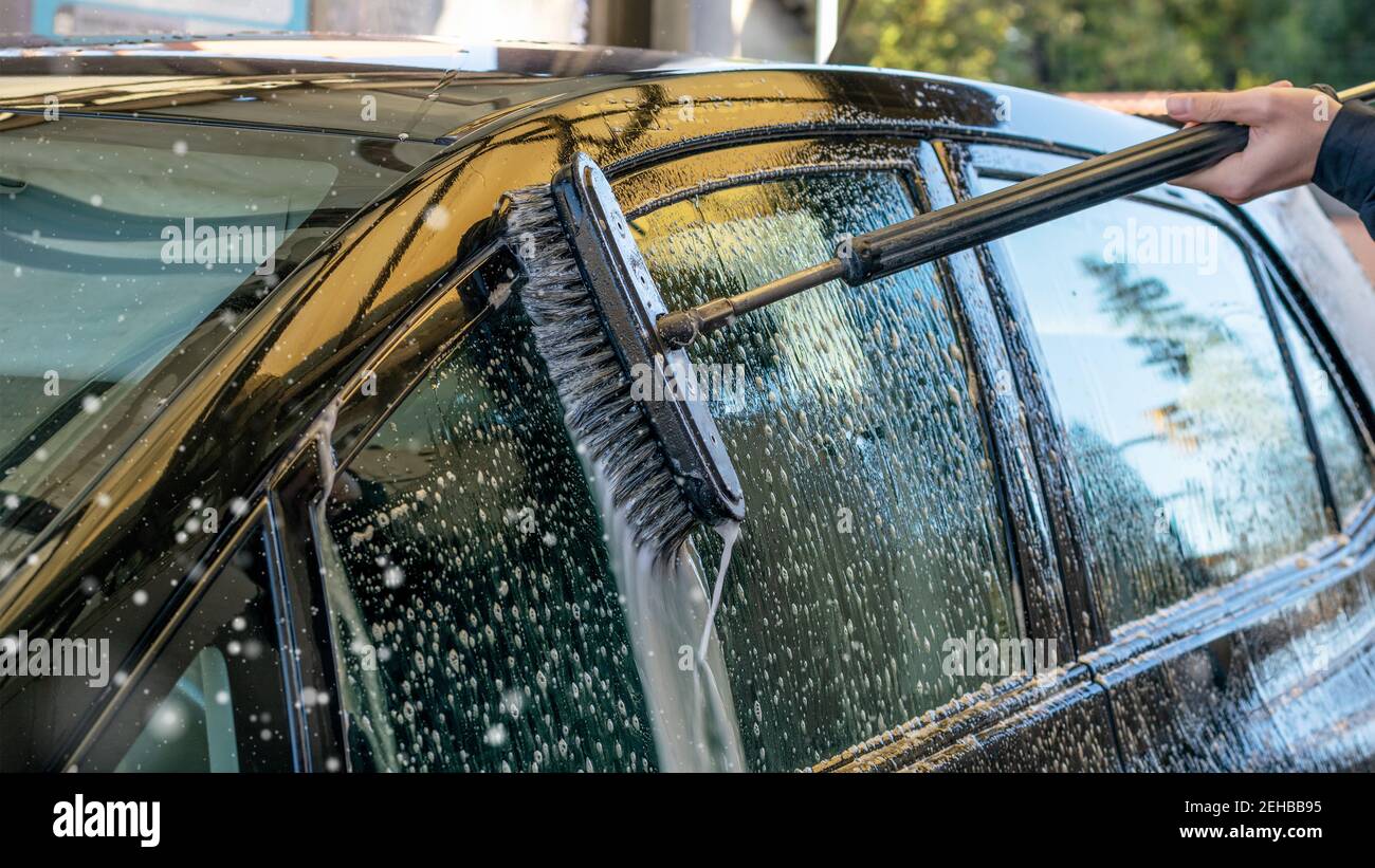 Outdoor car washing with a soapy brush. Car window detail washing with ...