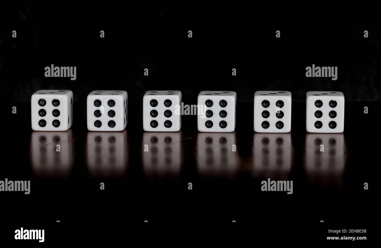 Six dice, all showing six, on a table with reflection and black ...