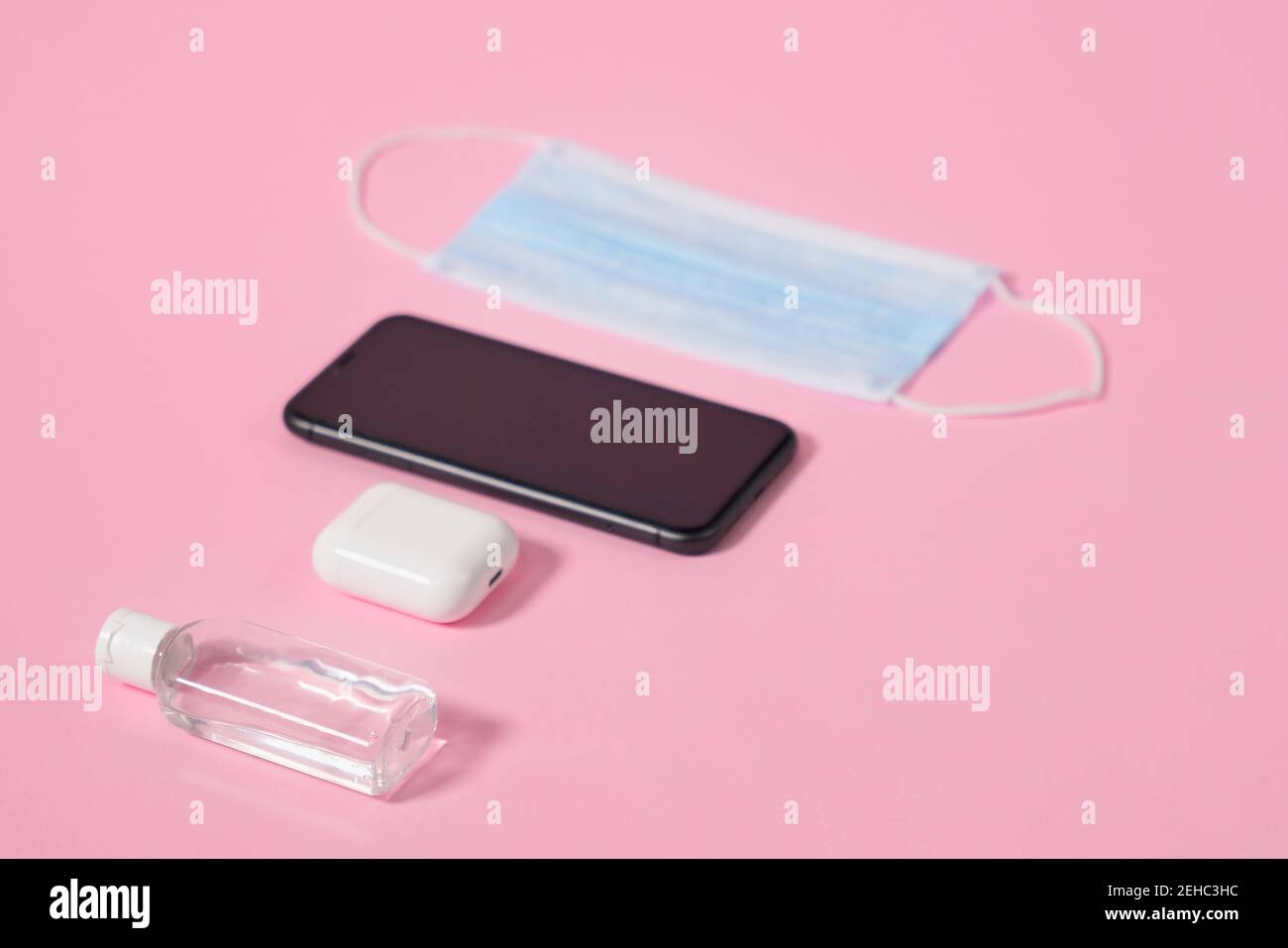 Medical blue mask, antiseptic and phone with headphones on pink ...