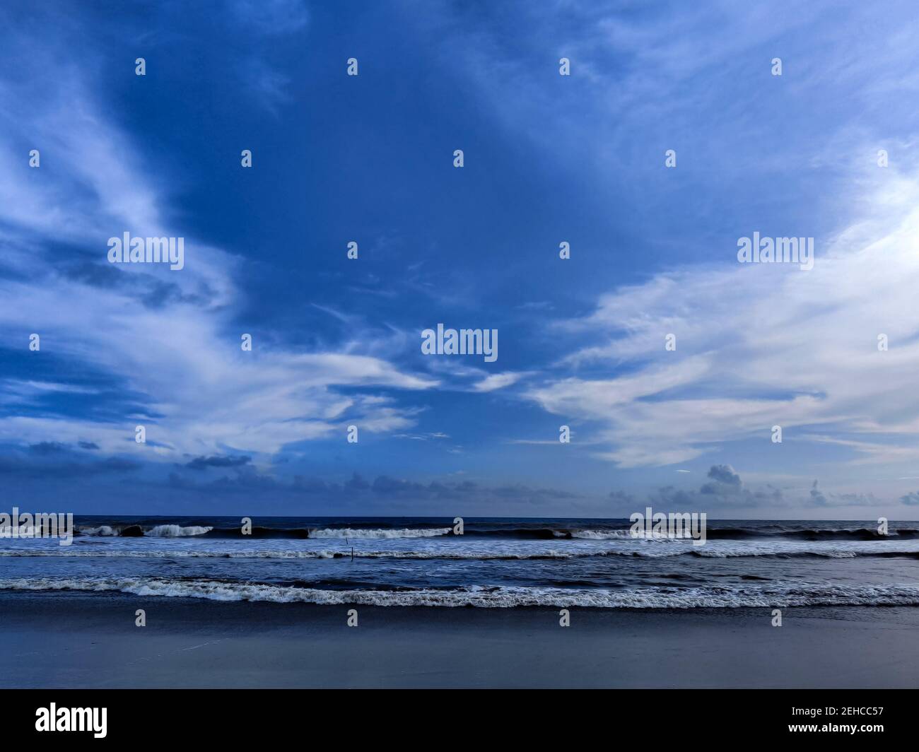 Natural view of strong waves on the sandy beach under a wispy sky ...