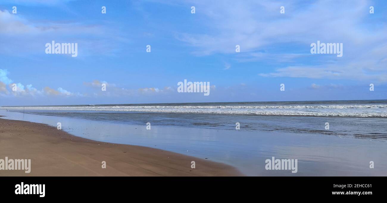 Natural view of soft waves on the sandy beach under a wispy sky ...