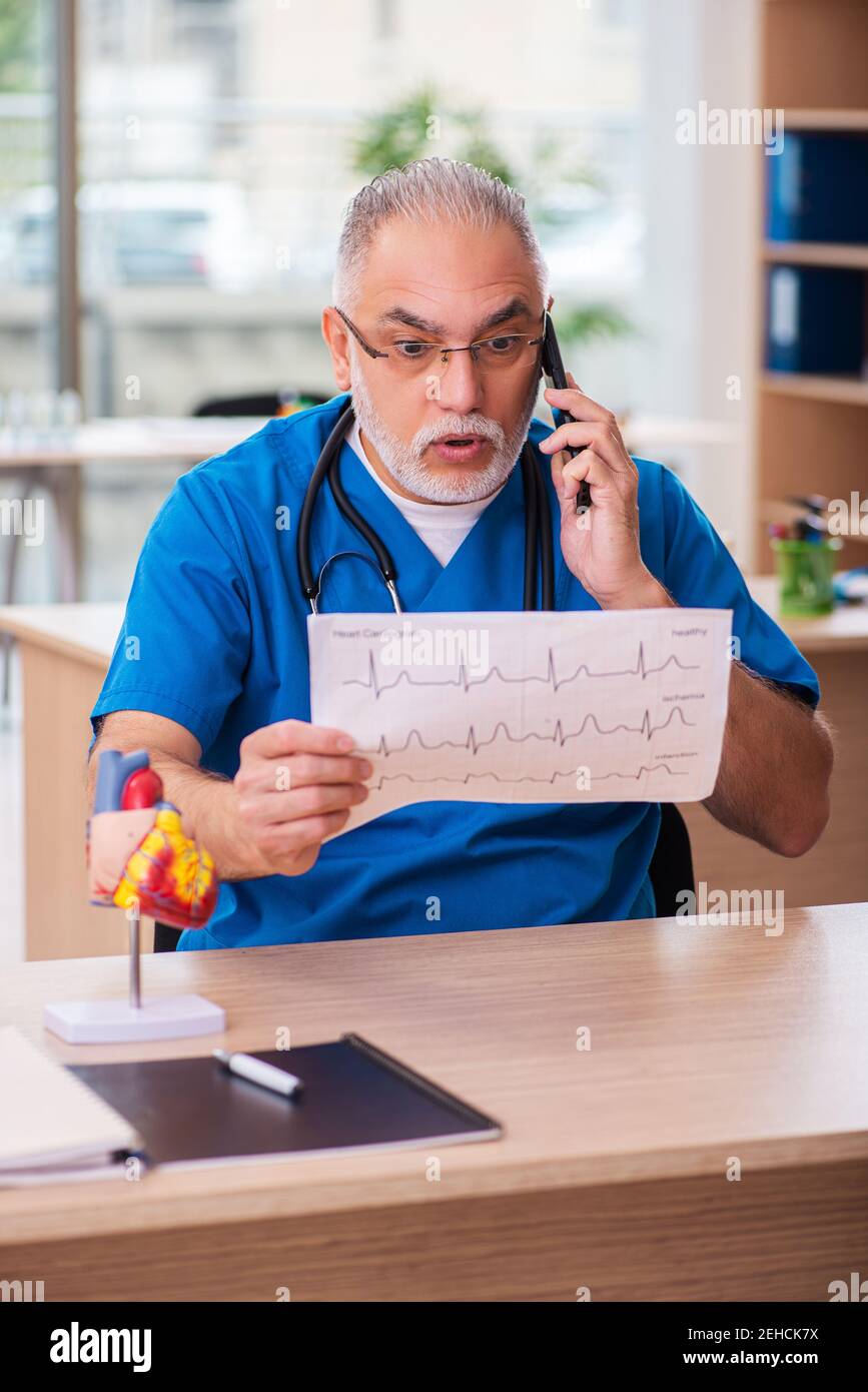 Old doctor cardiologist working in the clinic Stock Photo - Alamy