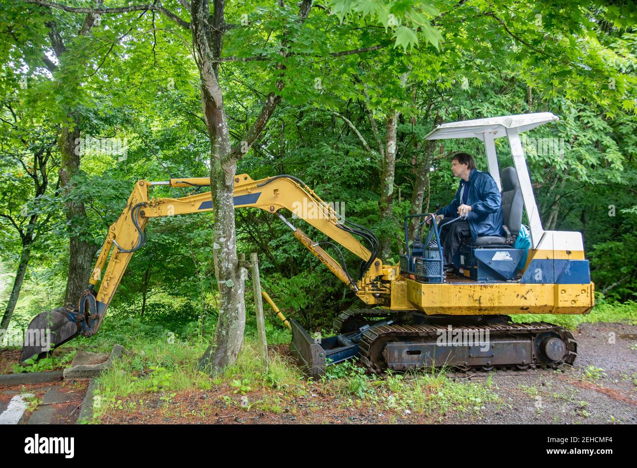 Earthworks with the excavator in nature. The man works with a small ...