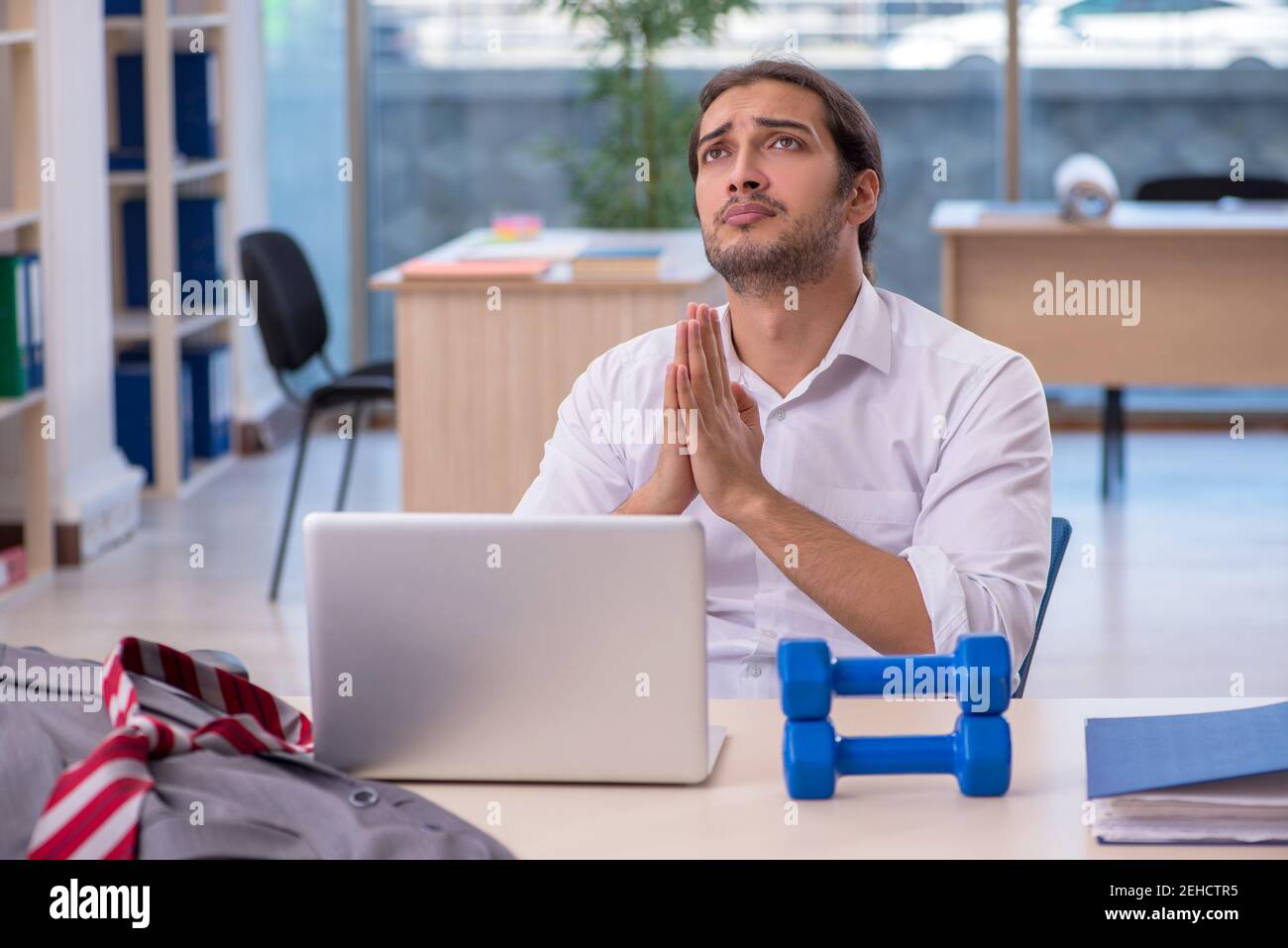 Young employee doing sport exercises at workplace Stock Photo - Alamy