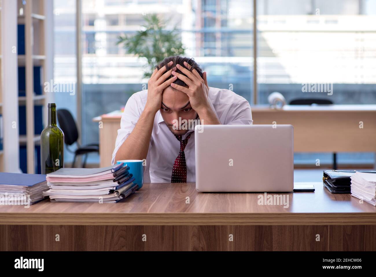 Young alcohol addicted employee working in the office Stock Photo - Alamy