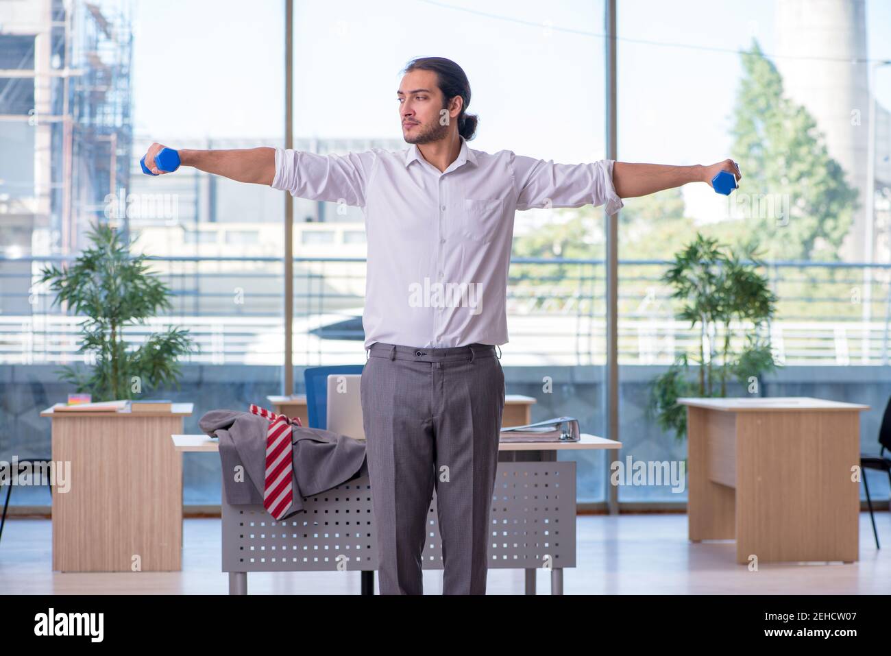 Young employee doing sport exercises at workplace Stock Photo - Alamy