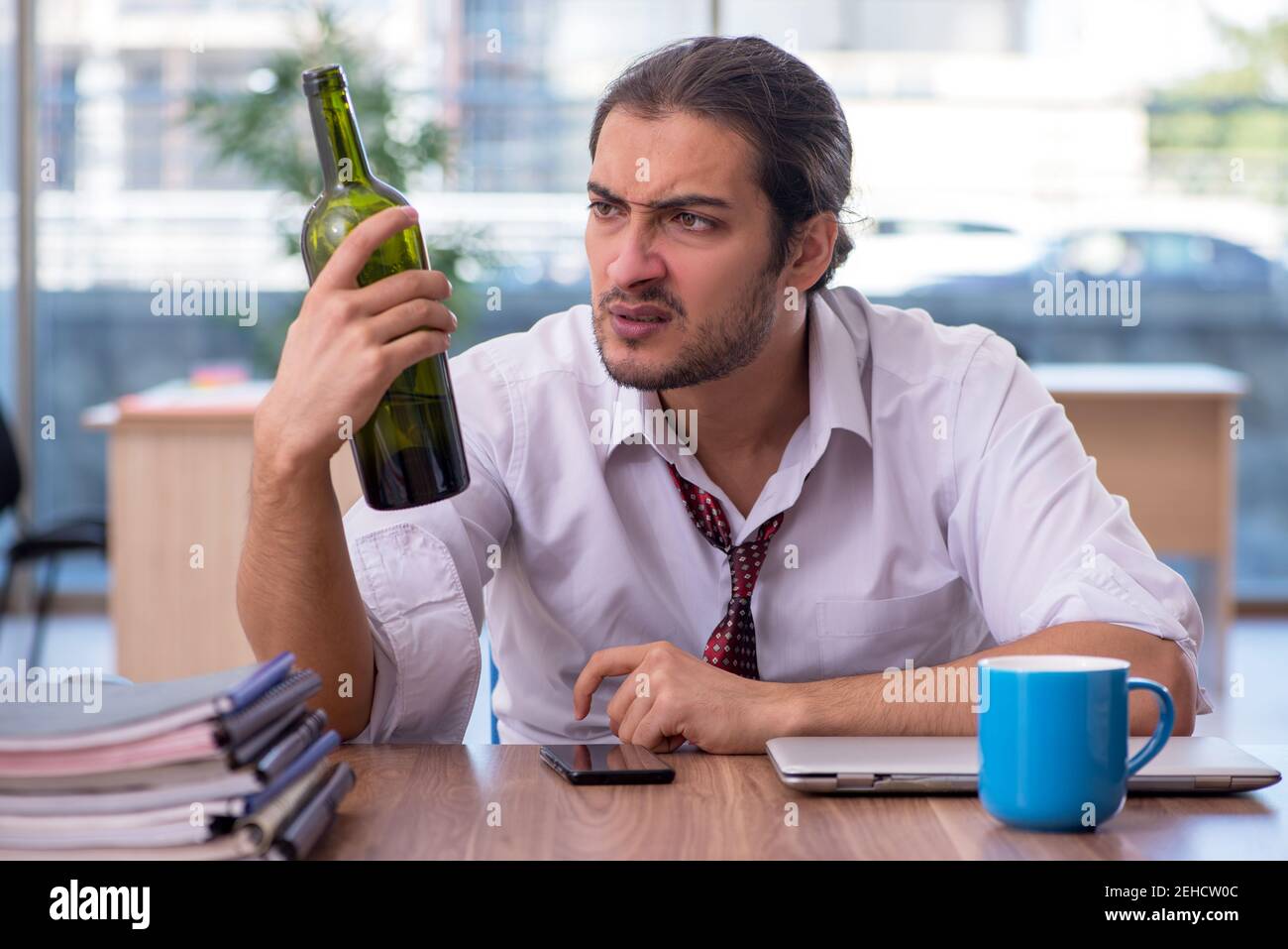 Young alcohol addicted employee working in the office Stock Photo - Alamy