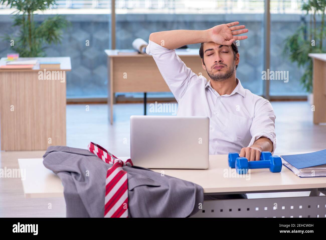 Young employee doing sport exercises at workplace Stock Photo - Alamy