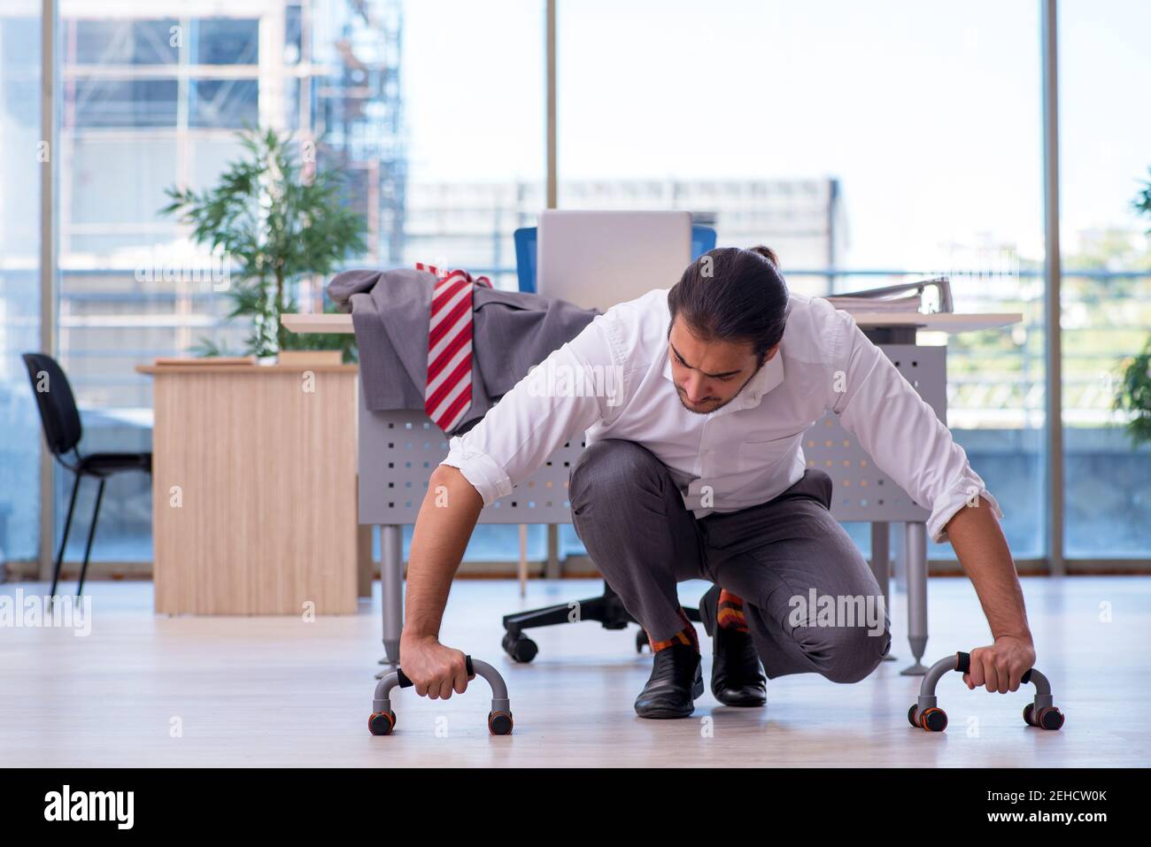 Young employee doing sport exercises at workplace Stock Photo - Alamy
