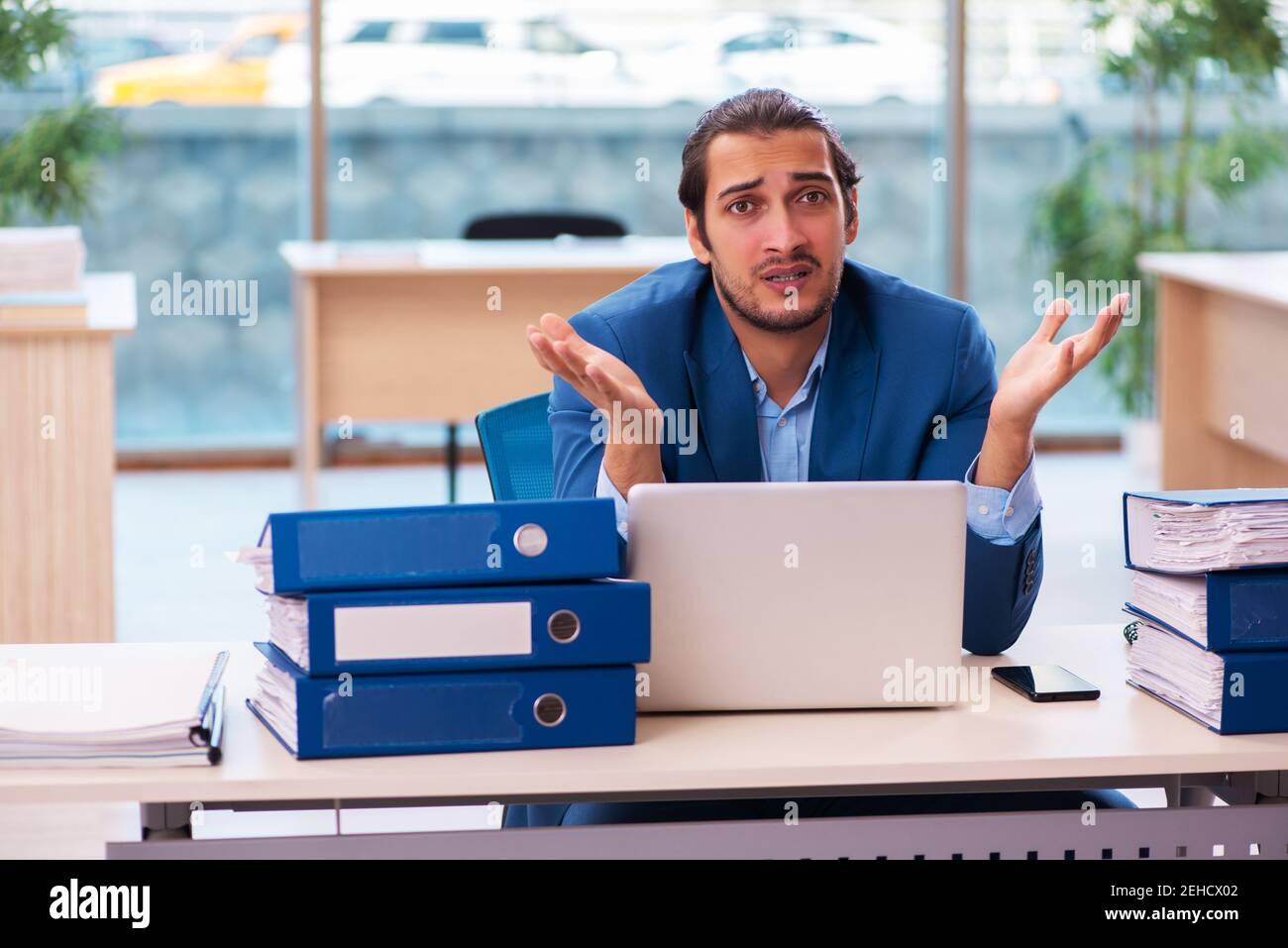 Young employee and too much work in the office Stock Photo - Alamy
