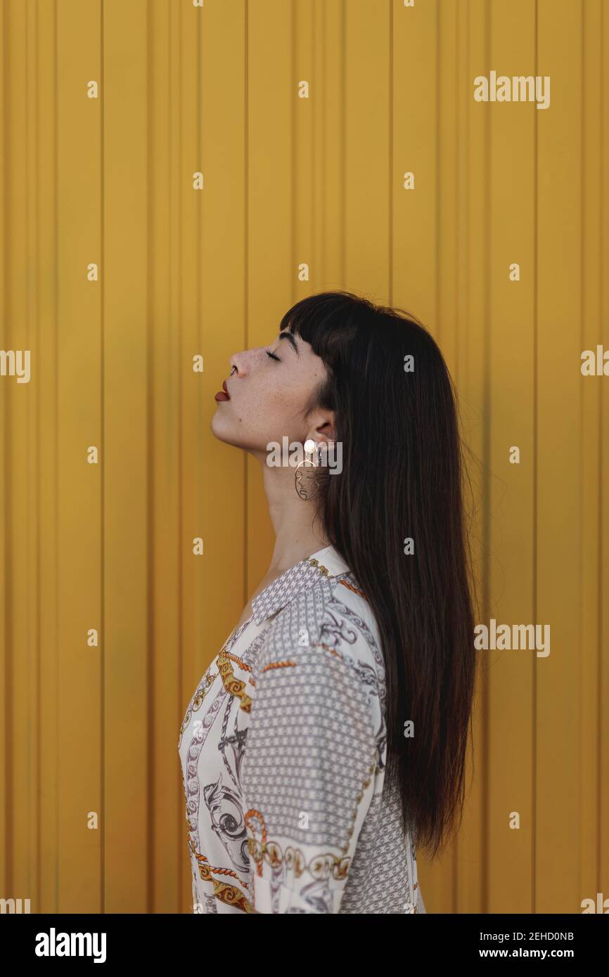 Side view of stylish young ethnic female with long dark hair in trendy ...