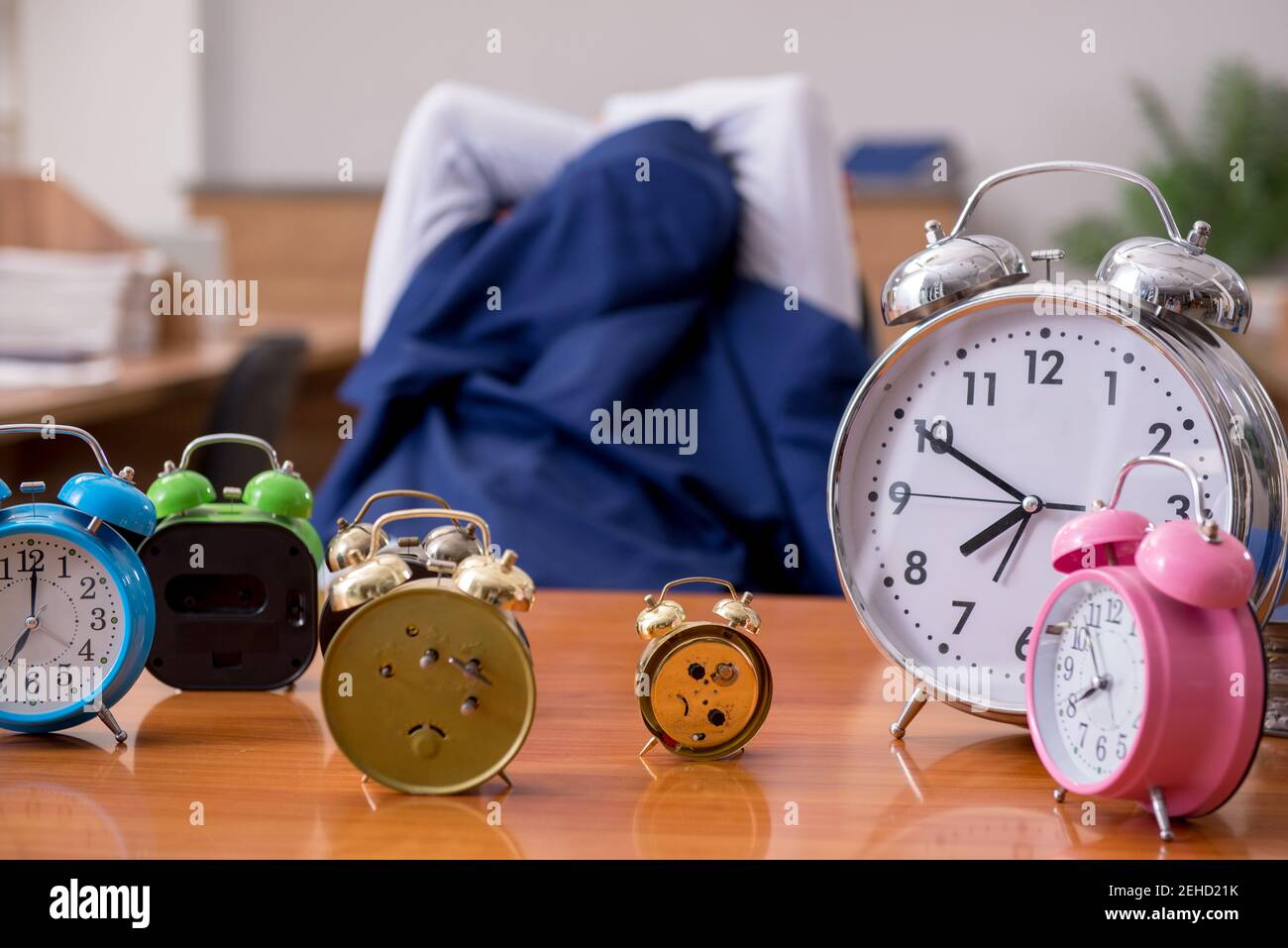 Young businessman sleeping in the office in time management concept ...