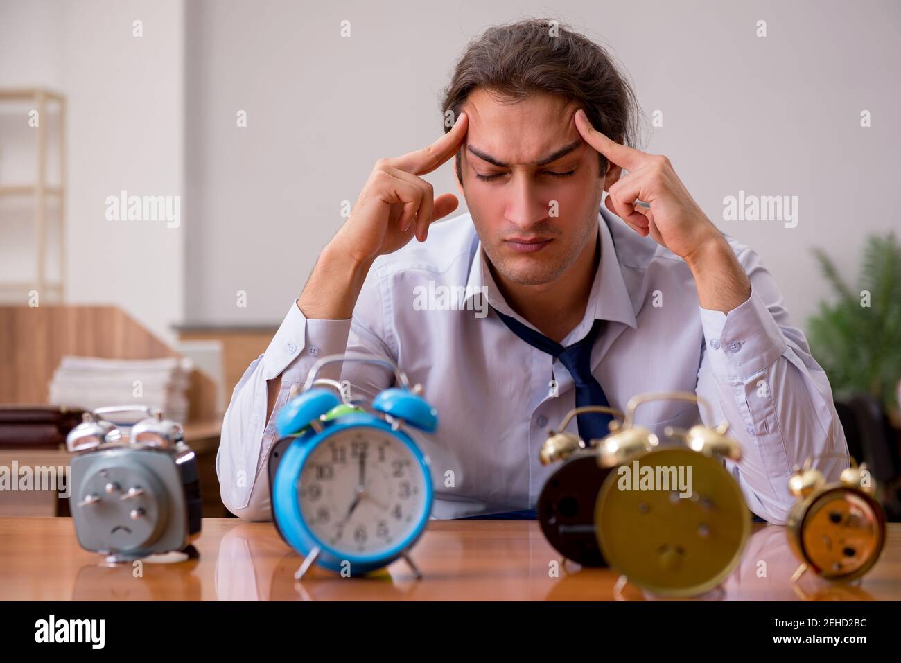 Young businessman sleeping in the office in time management concept ...