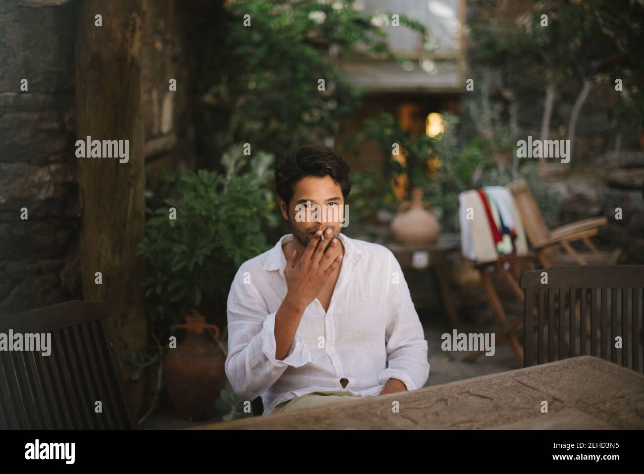 Young dark haired boy smoking a cigar while sitting on a patio Stock ...