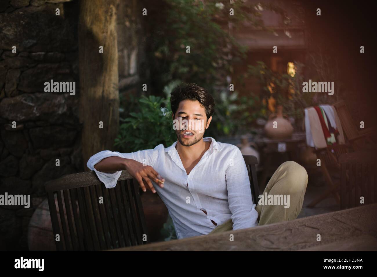 Young dark haired boy smoking a cigar while sitting on a patio Stock ...
