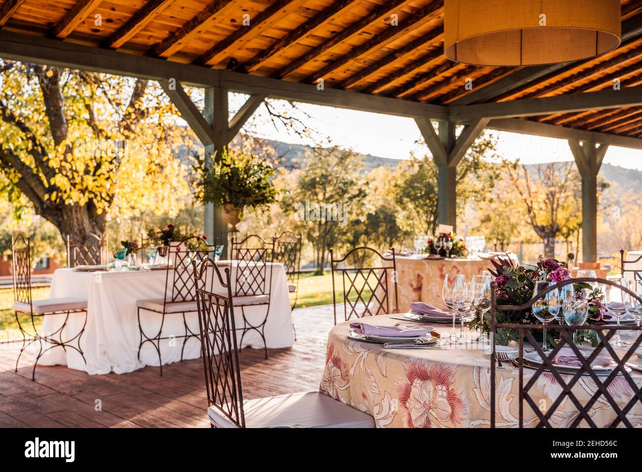 Spacious veranda with plates wineglasses and cutlery placed on tables ...