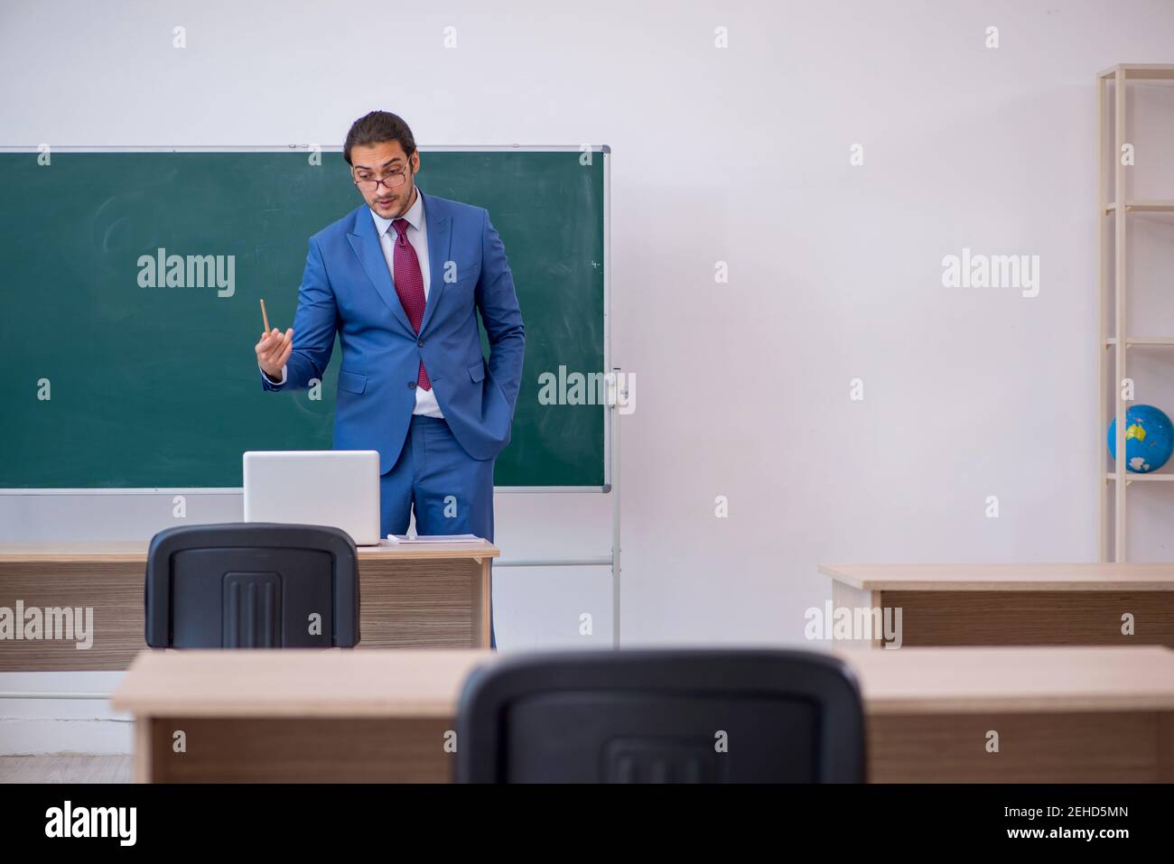 Young teacher in suit in front of green board Stock Photo - Alamy