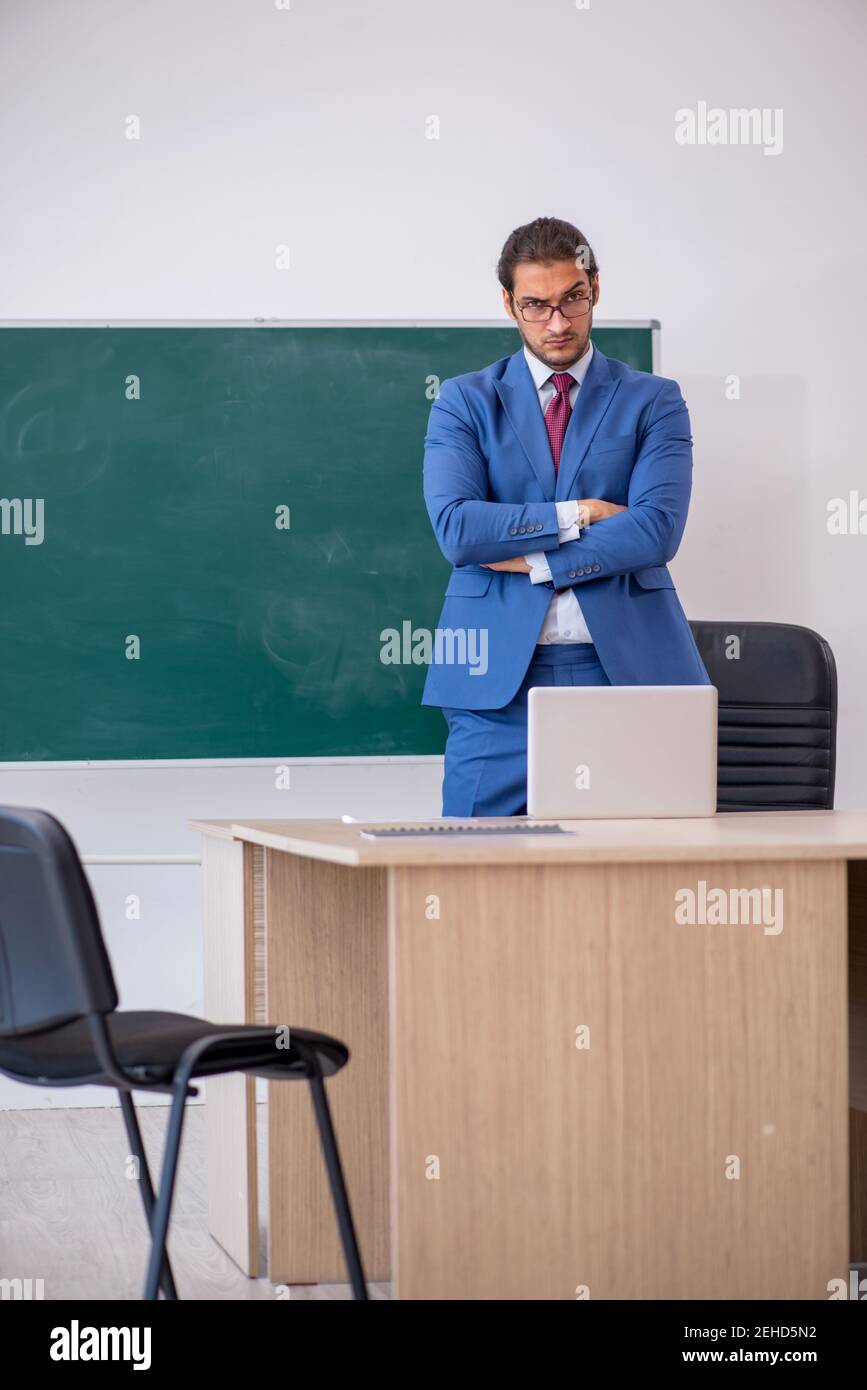 Young teacher in suit in front of green board Stock Photo - Alamy