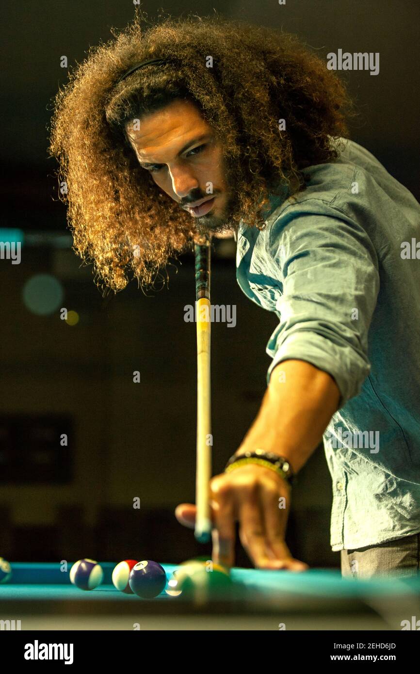 Crop focused bearded male hitting ball with cue while playing game in ...