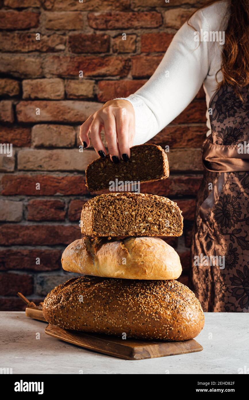 Crop anonymous female baker demonstrating soft fresh bread with crunchy ...