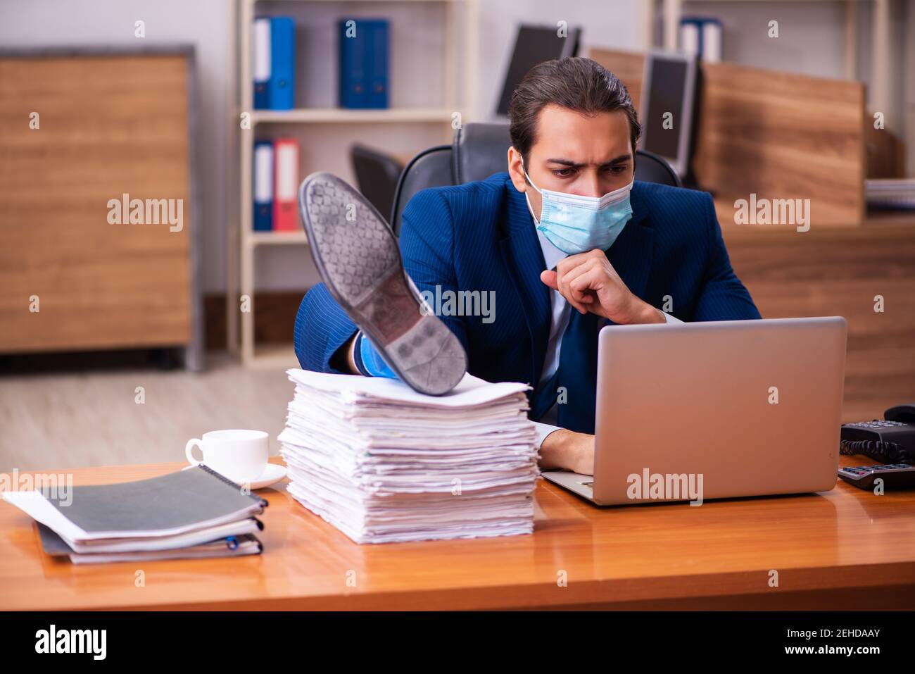 Young employee working in the office wearing mask Stock Photo - Alamy