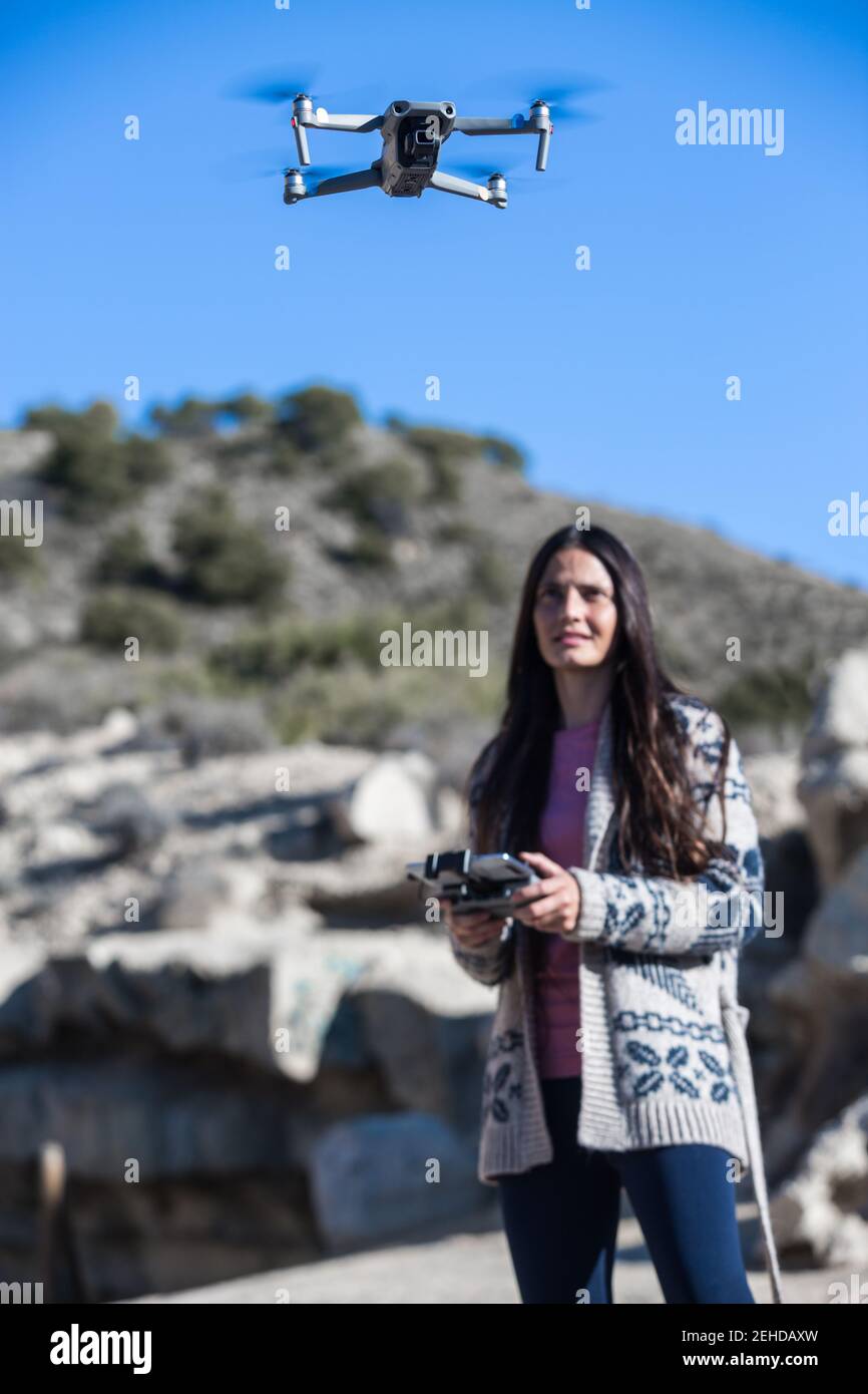 Smiling female with remote controller standing in nature and operating ...